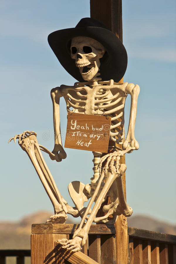 cowboy-skeleton-sits-against-post-sign-weathered-wooden-54120931 - PHX Fray